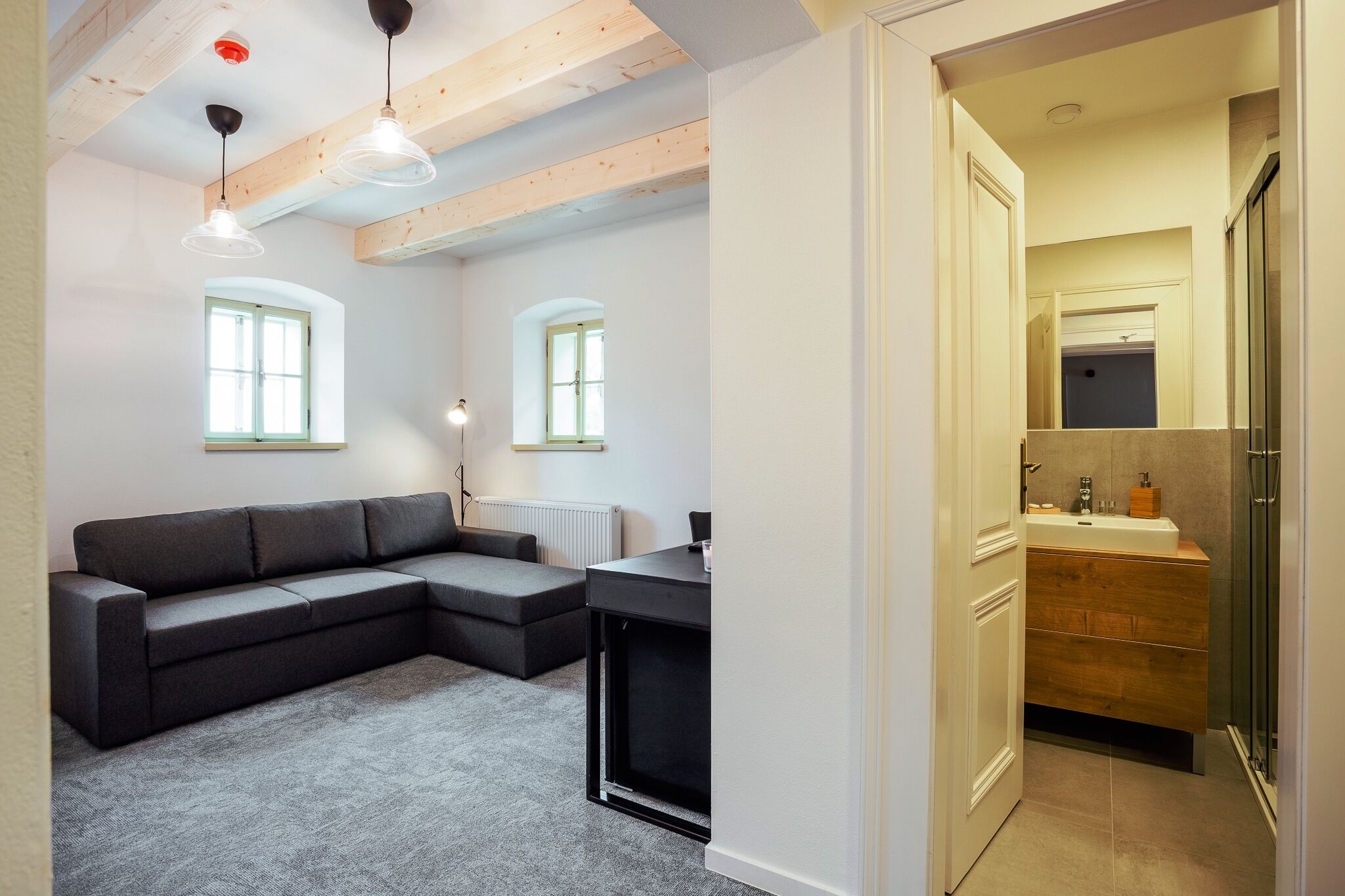Uma sala de estar moderna com sofá modular, uma escrivaninha preta e iluminação pendente.