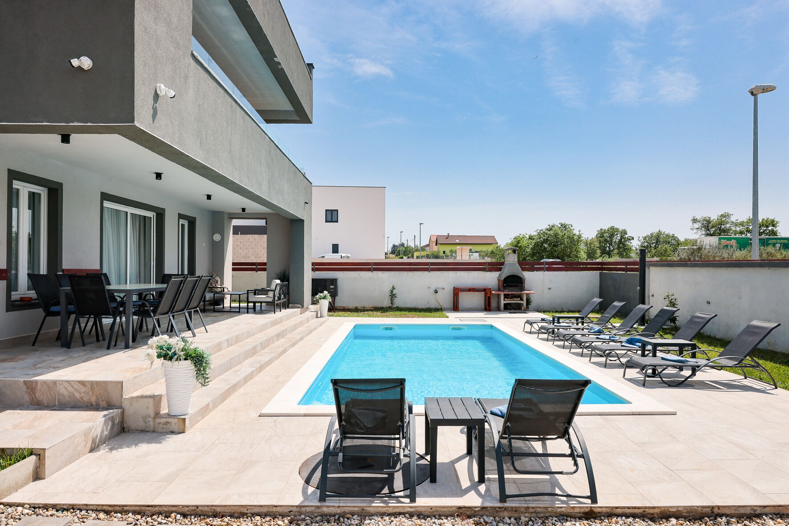 Uma área de piscina moderna ao ar livre, com espreguiçadeiras e espaço para refeições.
