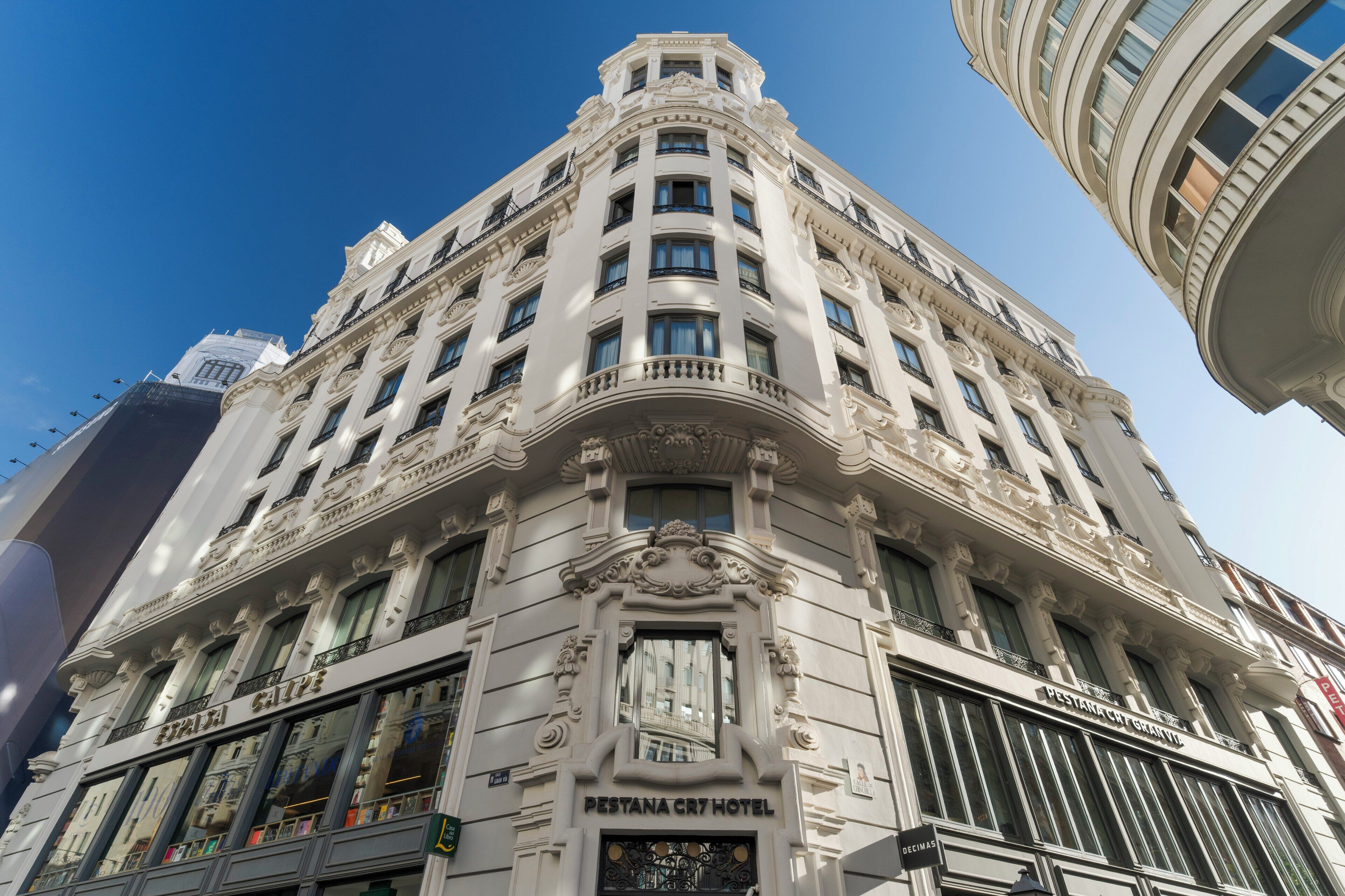 Um edifício de esquina com estilo arquitetônico clássico, com detalhes ornamentais e grandes janelas.
