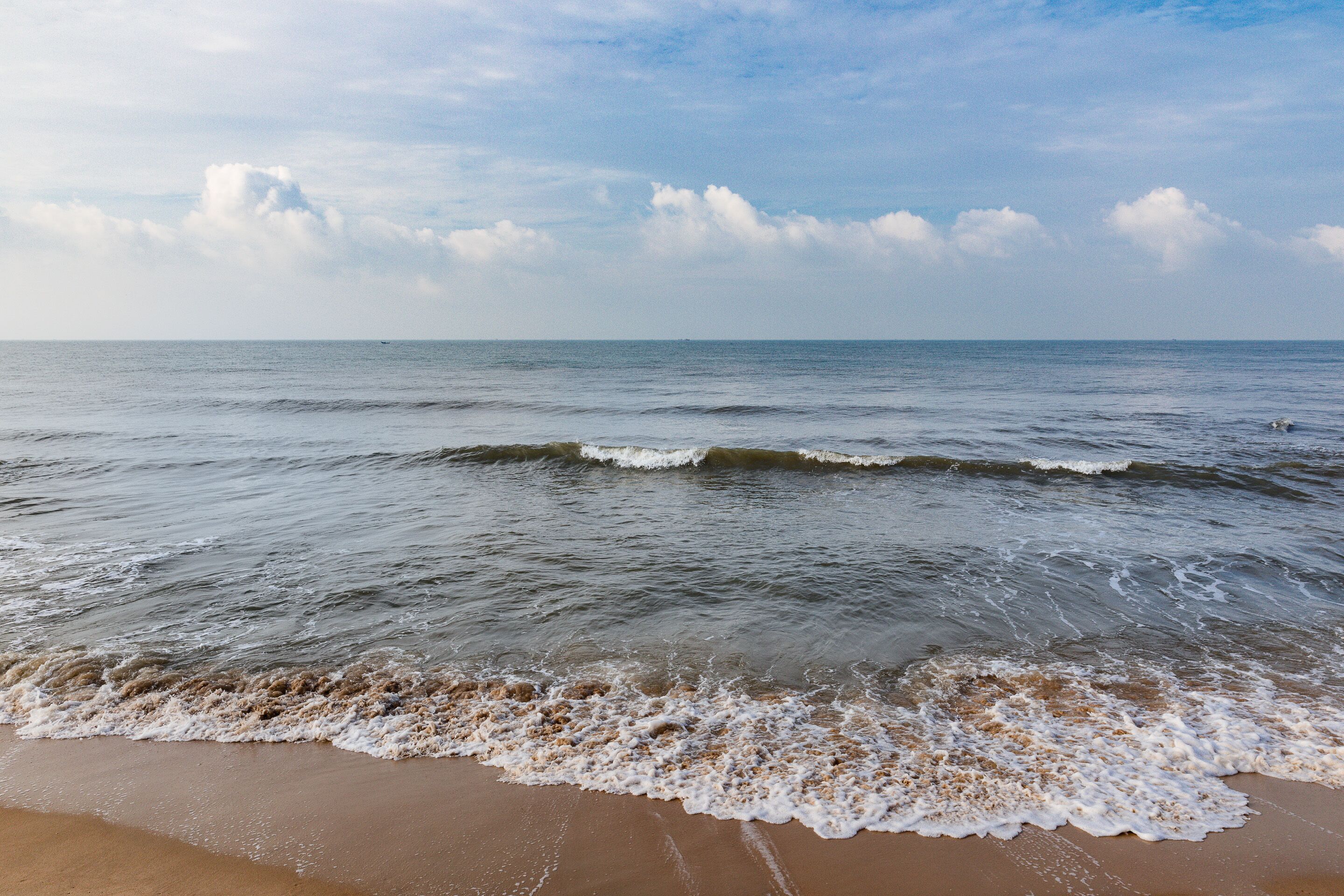 Uma praia com ondas suaves beijando a areia.