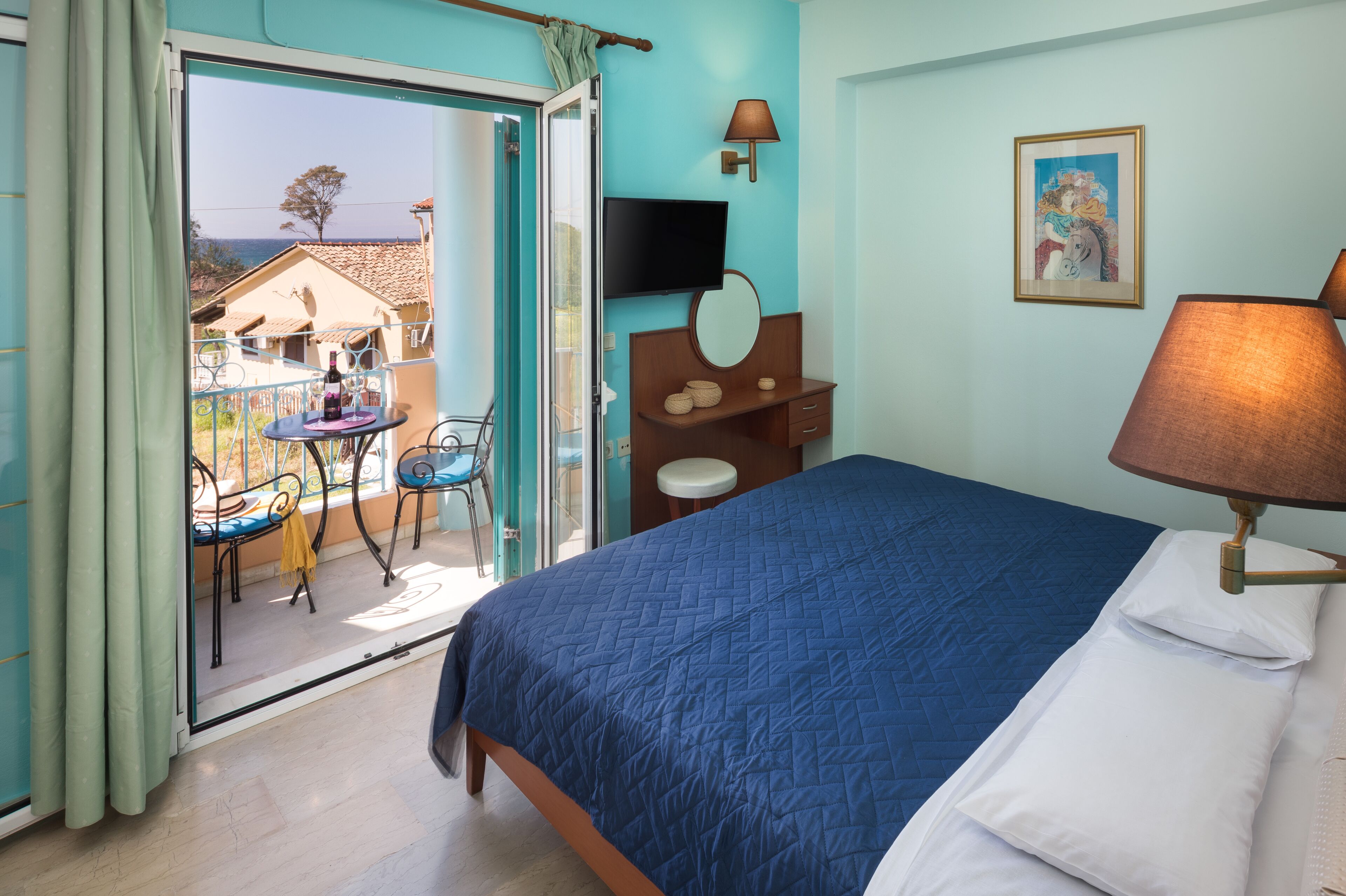 Quarto com cama, televisão, espelho e varanda com mesa e cadeiras.