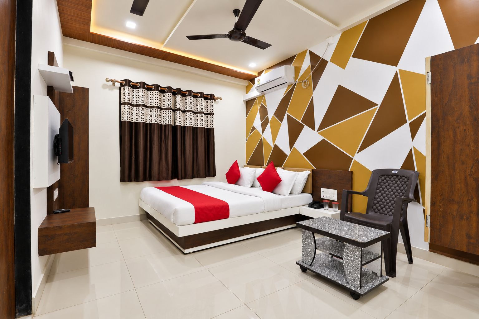 Quarto de hotel moderno com cama, escrivaninha, cadeira e ventilador de teto.