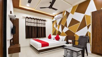 Quarto de hotel moderno com cama, escrivaninha, cadeira e ventilador de teto.