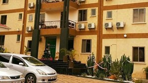 Um edifício com várias andares, varandas, aparelhos de ar condicionado e um carro estacionado na frente.