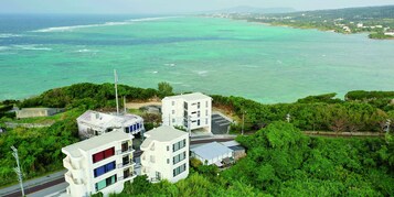 Zona residencial costeira com edifícios modernos, uma estrada e vista para o oceano.
