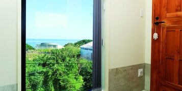Uma varanda com vista para o mar e vegetação.
