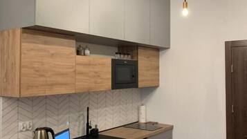 Cozinha moderna com armários cinza, bancadas de madeira, micro-ondas embutido e um laptop no balcão.