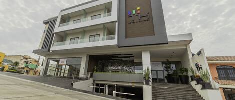 Um hotel moderno com estrutura de dois andares, entrada coberta e escadaria que leva à entrada.