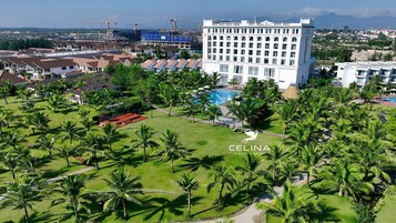 Resort com um edifício grande, piscina e palmeiras.