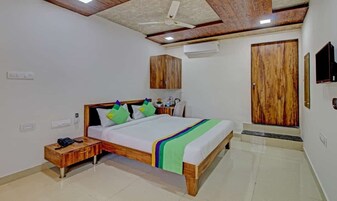 Quarto com cama de madeira, mesa de cabeceira, guarda-roupa e ventoinha no teto.