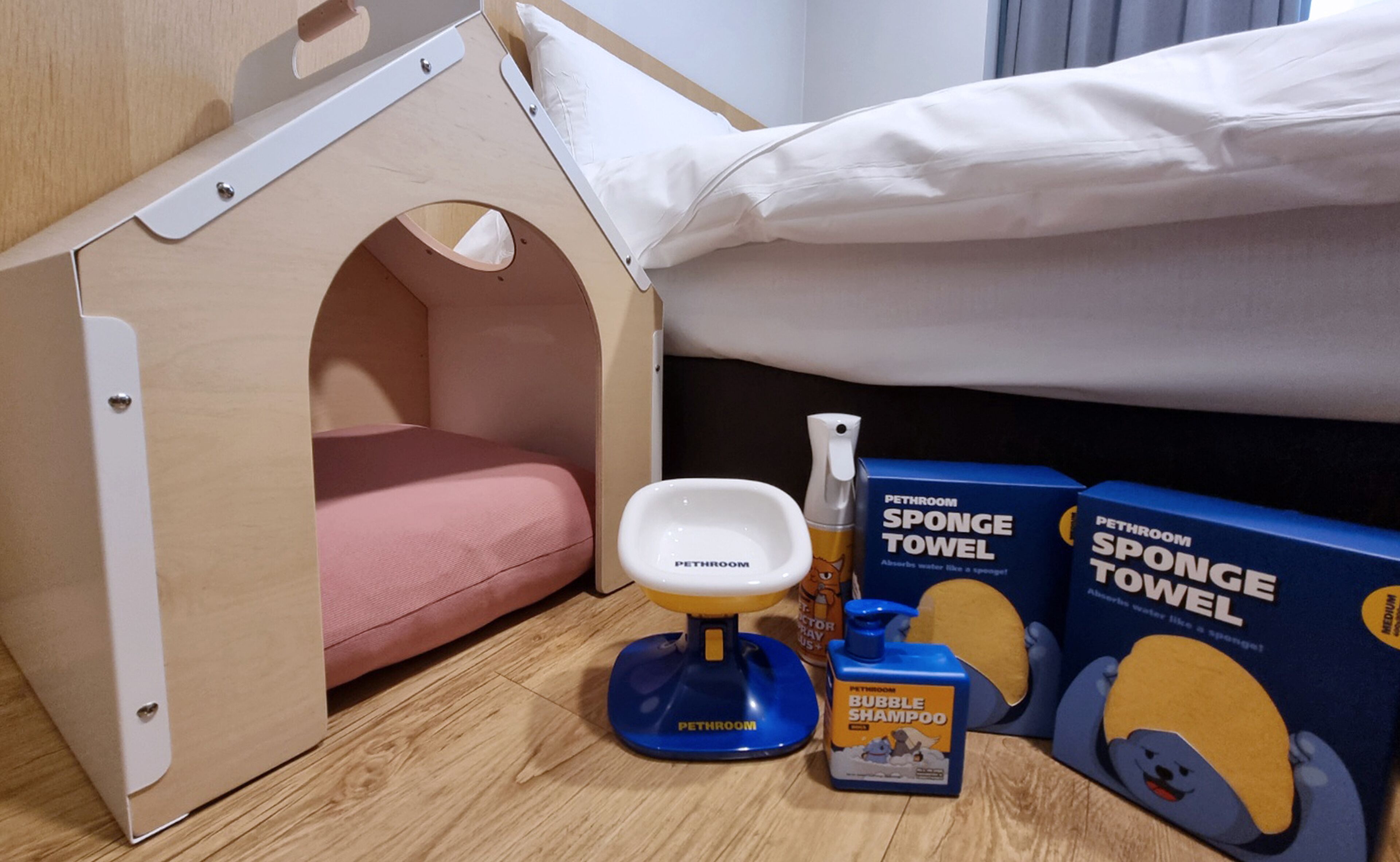 Casinha de brincadeira infantil com um banquinho rosa, uma cadeirinha de potty e duas caixas de produtos de banheiro Pethroom.