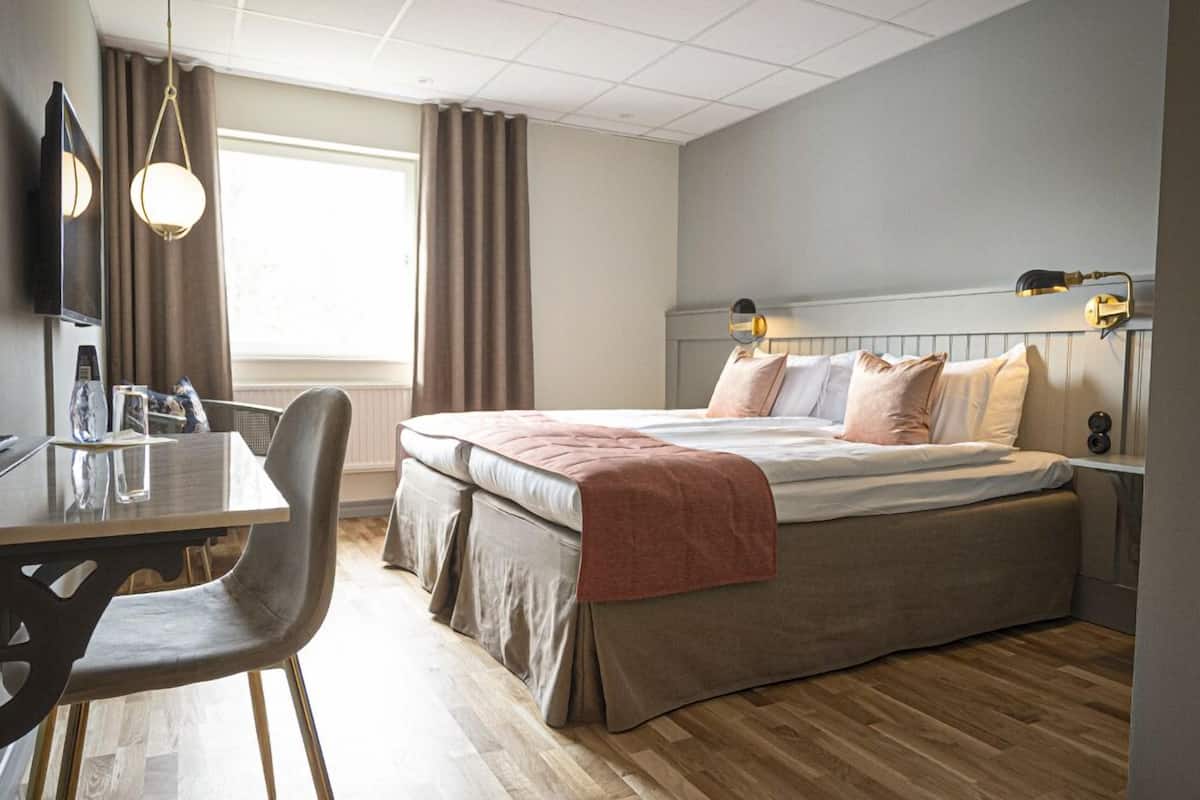 Quarto moderno com cama, mesa de cabeceira e escrivaninha com cadeiras.