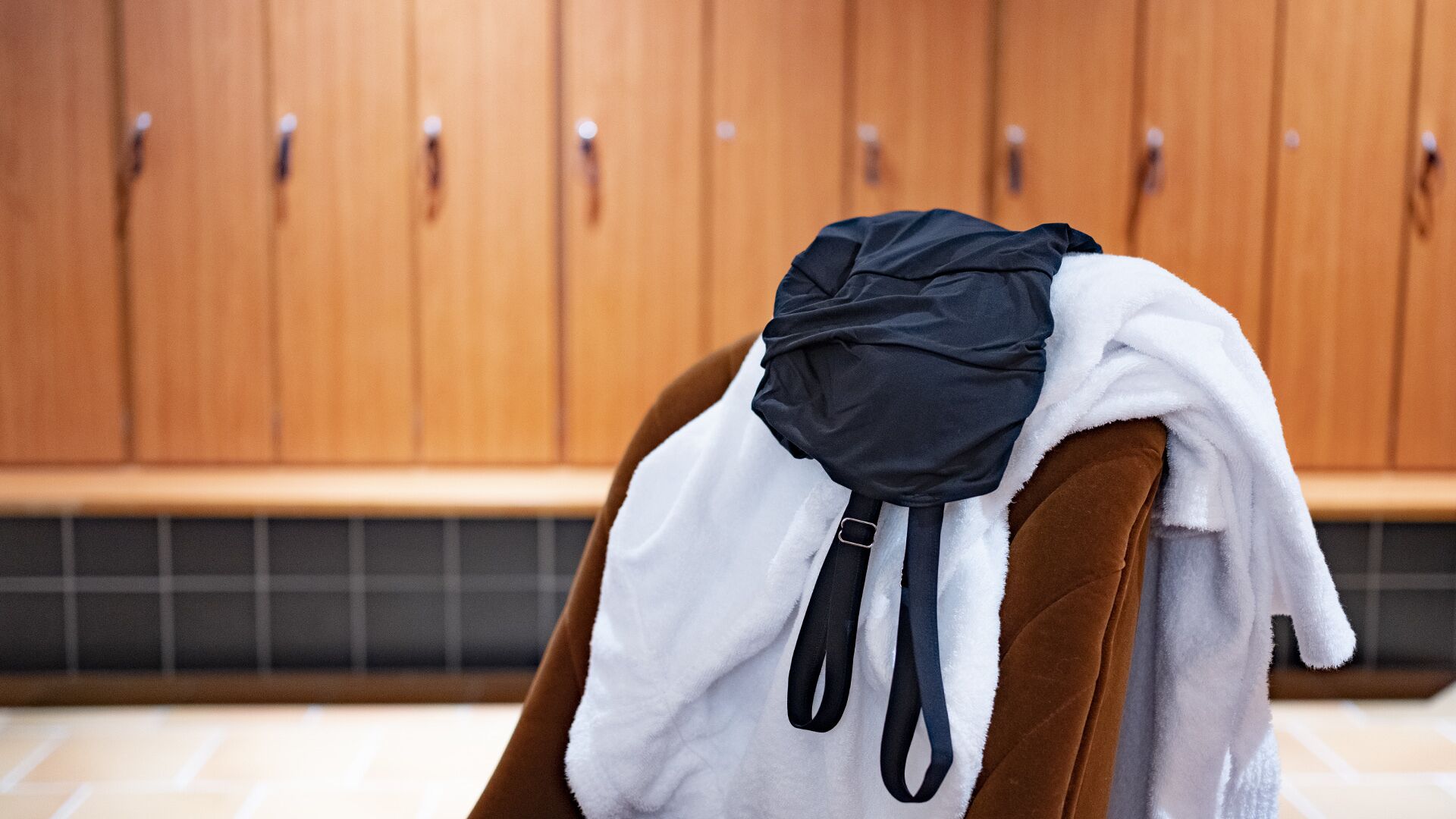 Um banco com uma mochila e uma toalha branca pendurada.