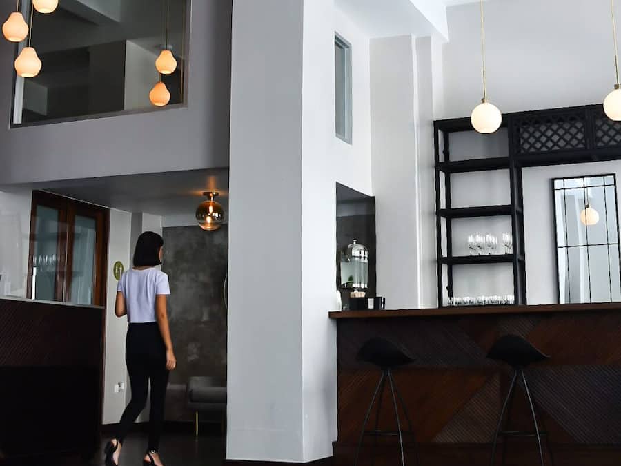 Decoração moderna com balcão de recepção, área de bar e luminárias pendentes.