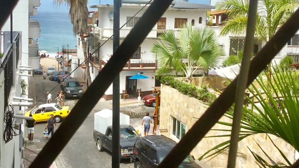 Uma rua costeira com edifícios, carros estacionados e palmeiras.