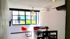 Um espaço moderno para viver, com área de refeições, sofá e uma cadeira vermelha.