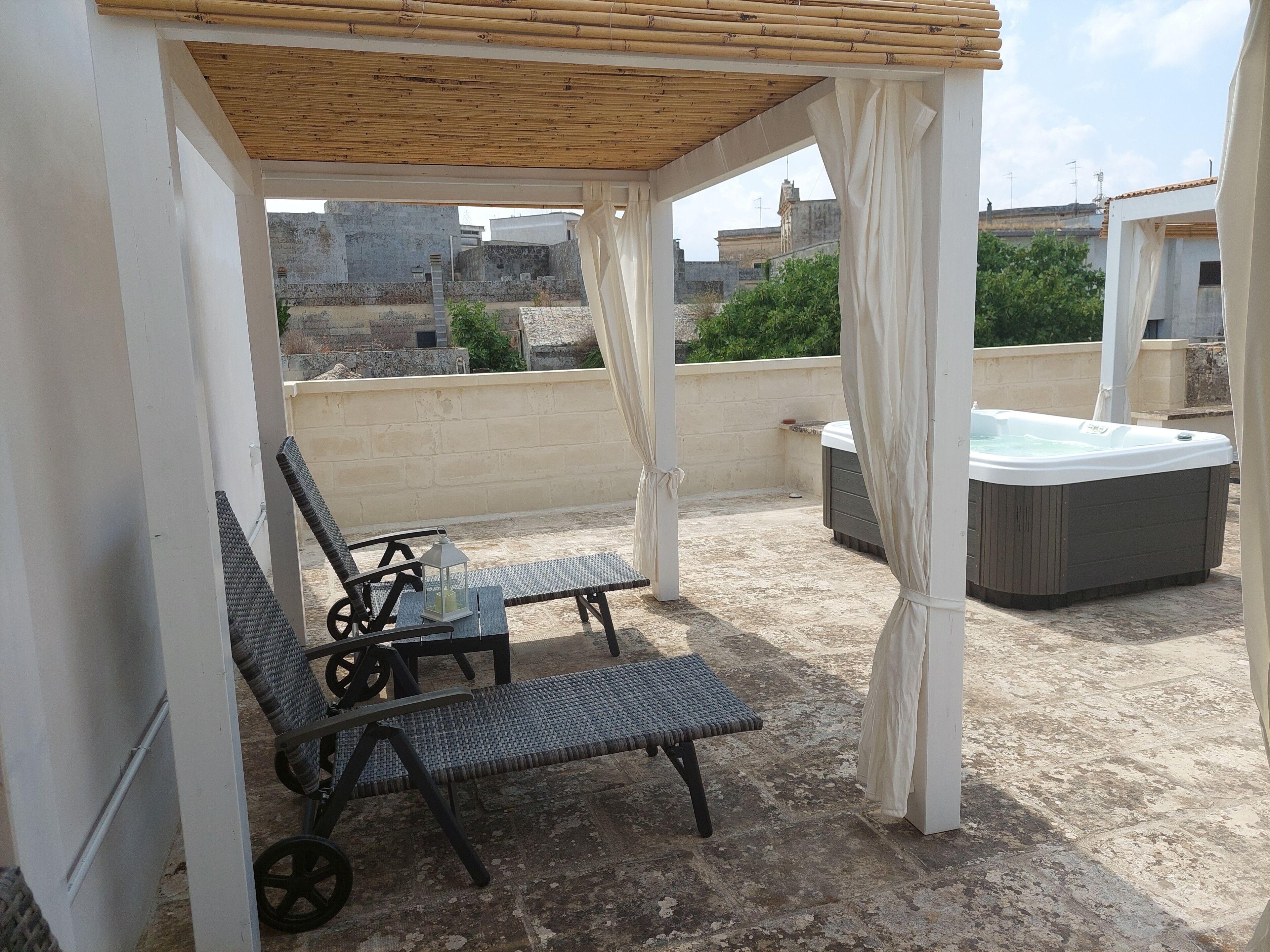 Uma área de estar coberta ao ar livre com hidromassagem, espreguiçadeiras e um pérgola.