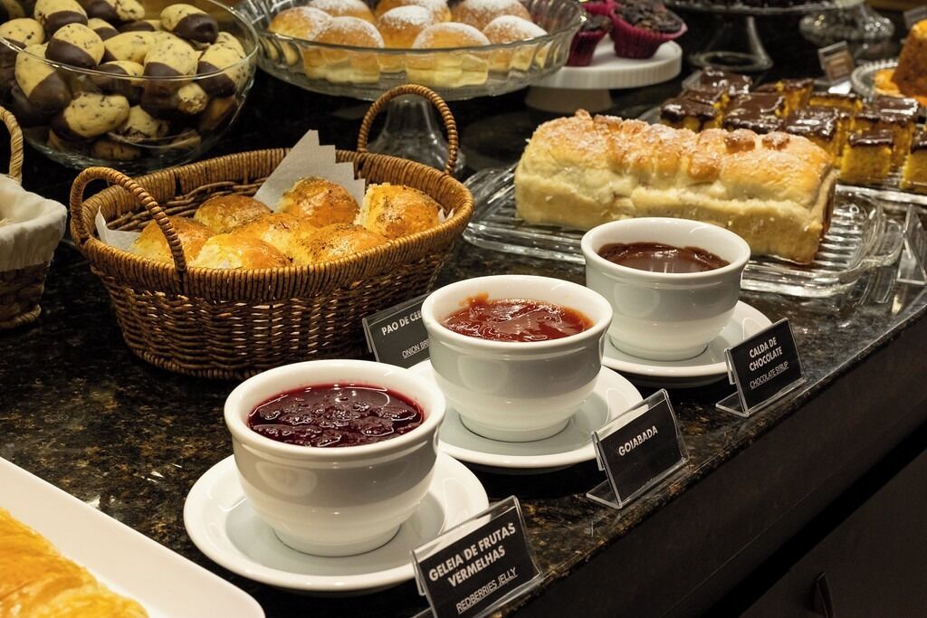 Buffet variado com diversas sobremesas, incluindo bolos, doces e compotas de fruta.