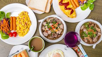 Uma mesa com diversos pratos, incluindo ovos mexidos, salsichas e uma tigela de sopa.