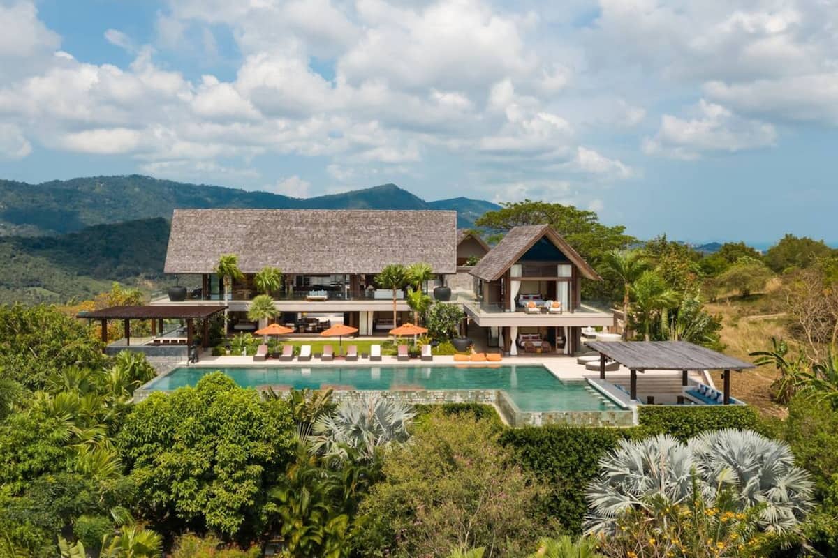 Um resort luxuoso com uma grande piscina, várias acomodações e uma paisagem montanhosa deslumbrante.