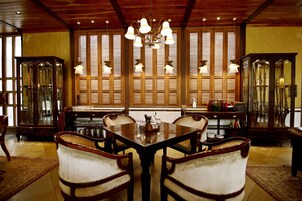 Uma sala de jantar com mesa e cadeiras de madeira, um candelabro e armários de madeira.