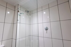 Casa de banho moderna com azulejos brancos e cabine de duche em vidro.