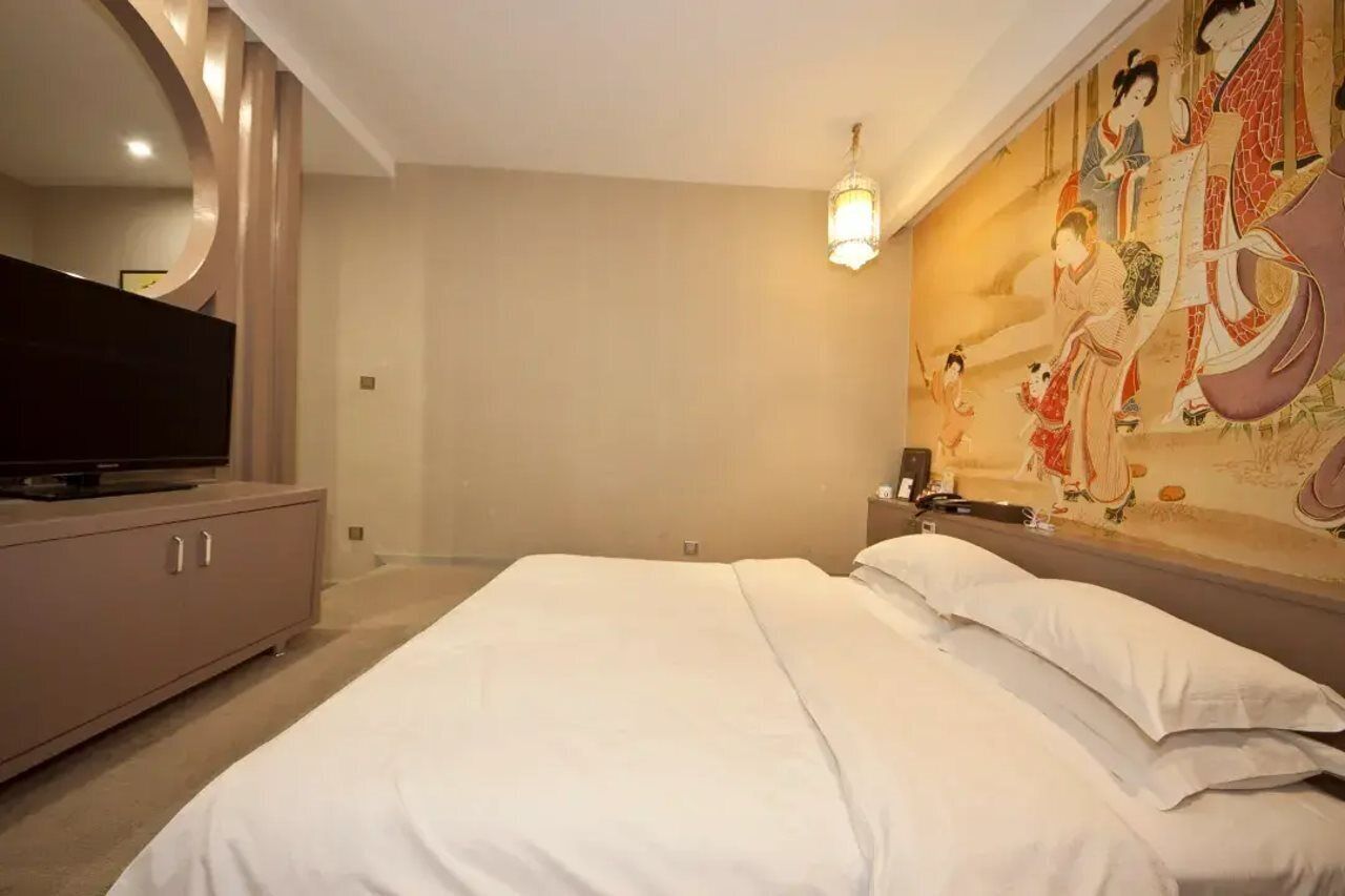 Quarto de hotel com uma cama, uma televisão num móvel e um mural na parede.