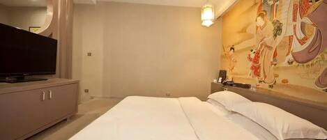 Quarto de hotel com uma cama, uma televisão num móvel e um mural na parede.