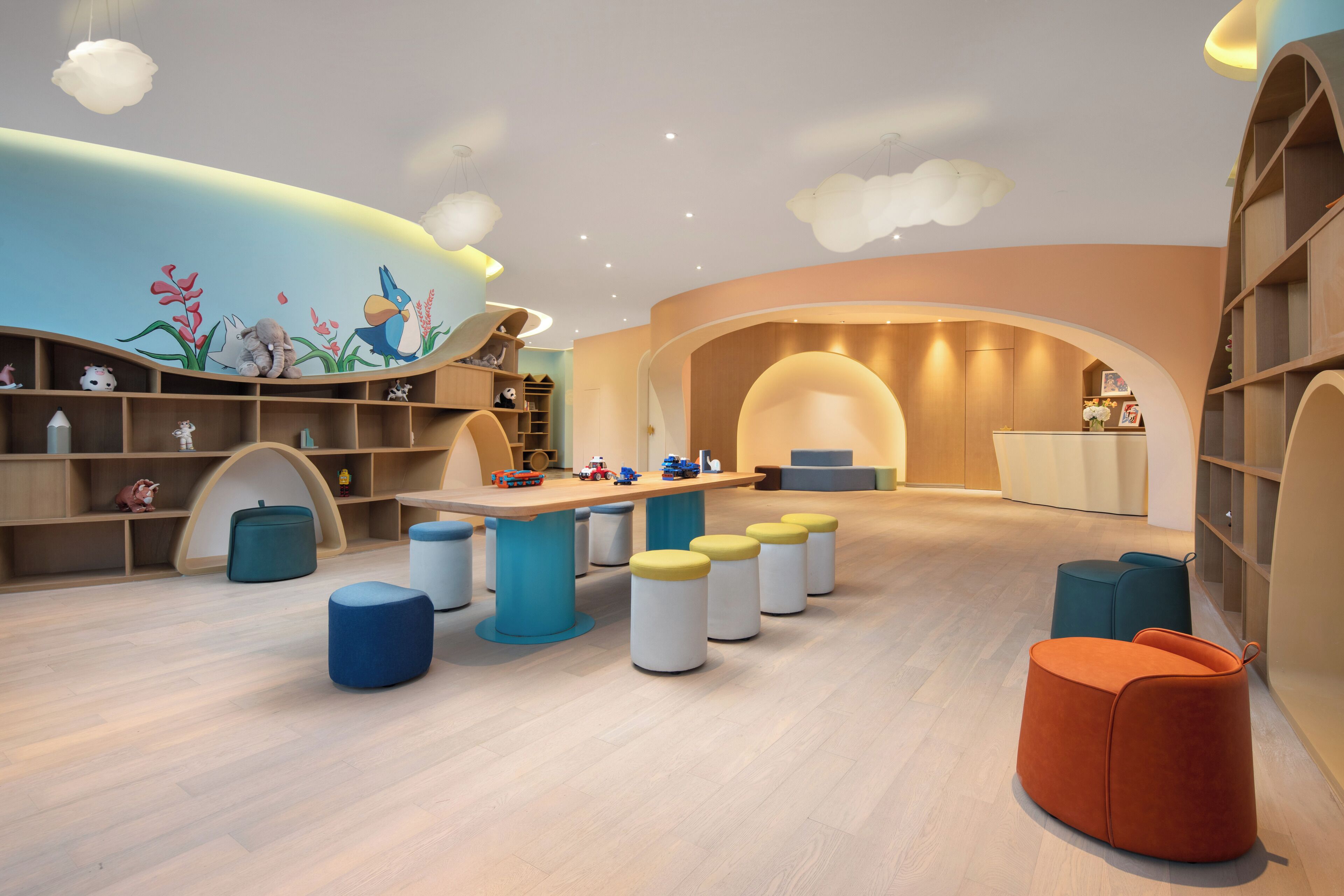 Uma sala de jogos infantil com teto curvo, painéis coloridos nas paredes e diversos móveis de recreação.