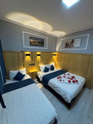 Quarto de hotel com duas camas, painéis de madeira, luminárias fixadas na parede e obras de arte emolduradas.