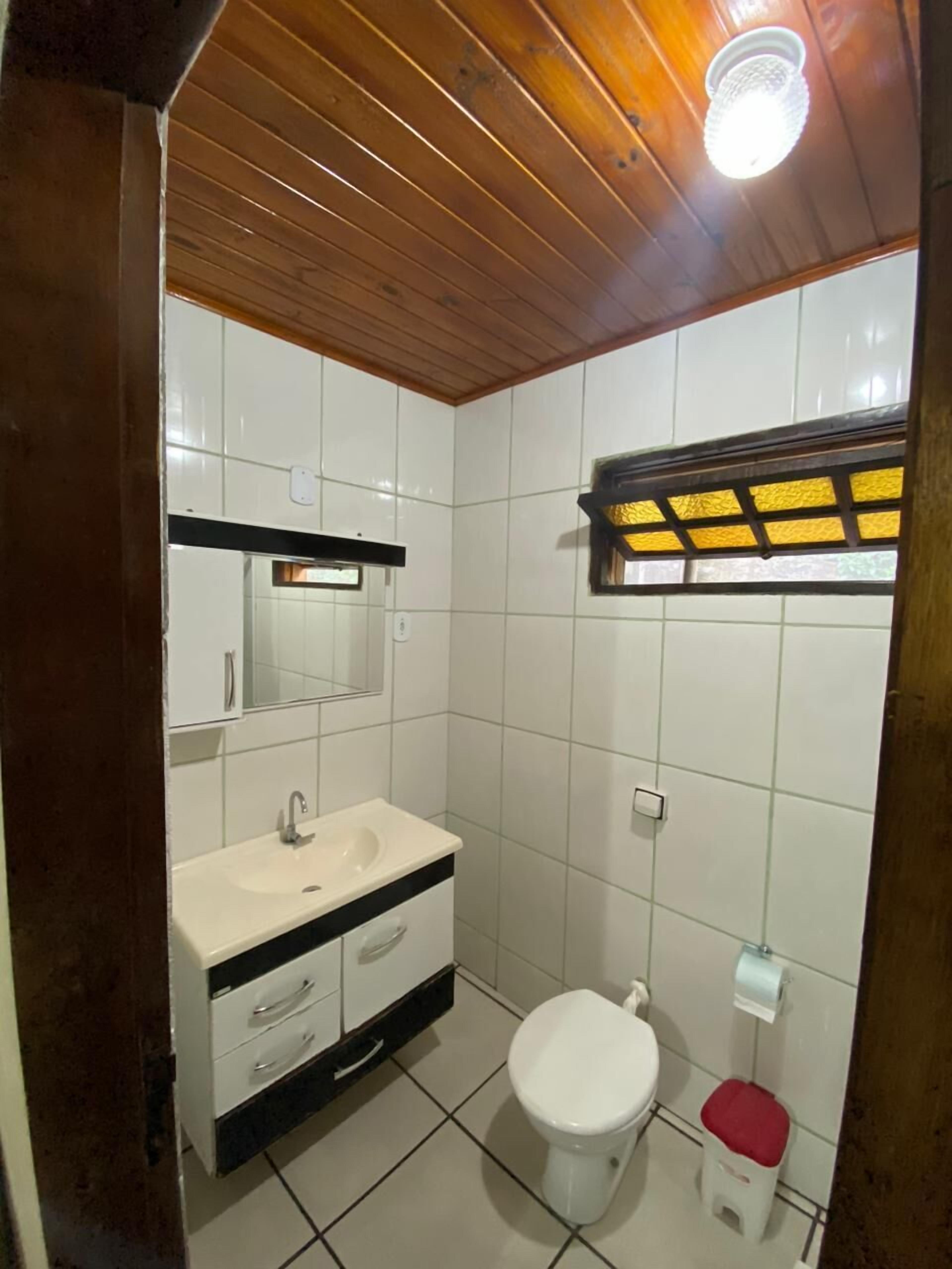 Casa de banho pequena e compacta com lavatório, espelho e sanita brancos.