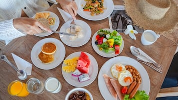 Mesa com diversos itens de café da manhã, incluindo panquecas, ovos e frutas.