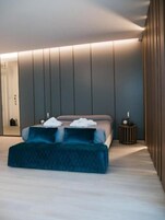 Quarto moderno com cama, mesas de cabeceira e luminária na parede.