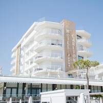 Um hotel com vários andares, varandas, uma placa vertical chamativa e uma área externa coberta.