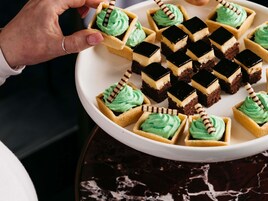 Um prato de sobremesas com cobertura verde e pedaços de chocolate.