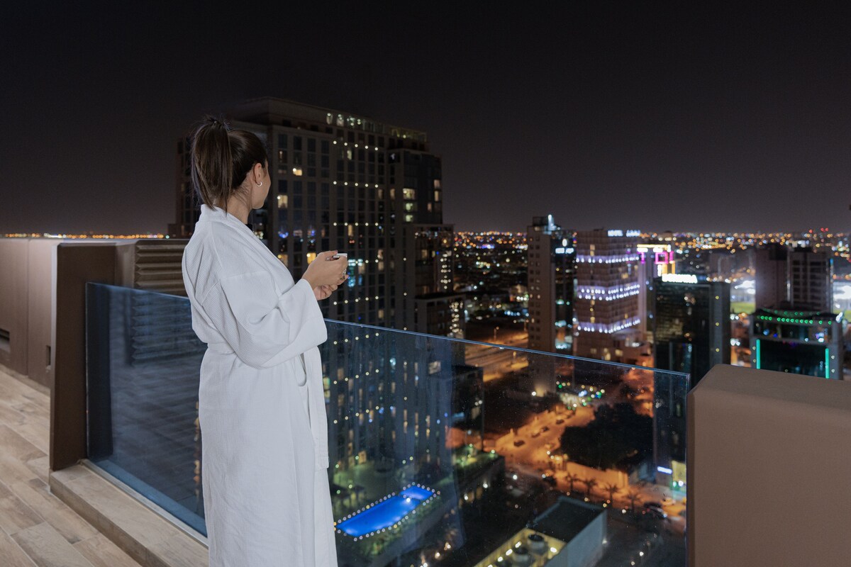 Uma pessoa está em uma varanda com vista para a cidade à noite.