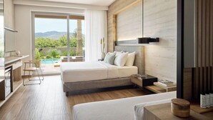 Quarto moderno com uma cama grande, uma escrivaninha e vista para uma piscina e vegetação.