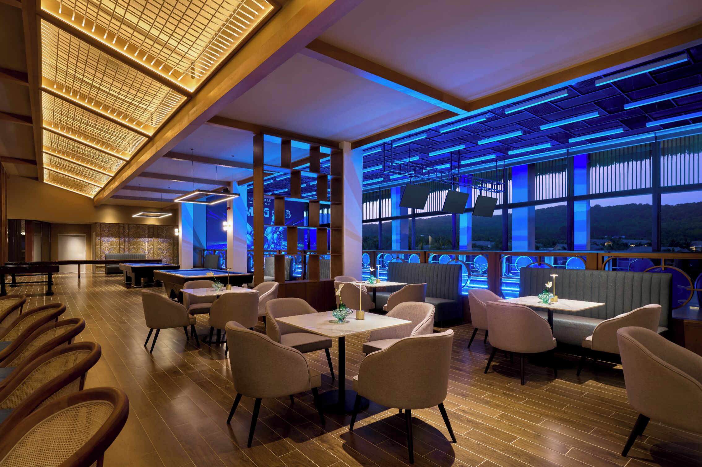 Um restaurante moderno com piso de madeira, mesas e cadeiras.