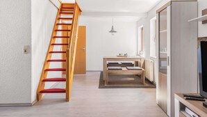 Um interior moderno com escada de madeira, área de jantar e televisão.