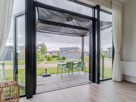 Quarto moderno com porta de correr de vidro que dá para um pátio externo com mesa e cadeiras.