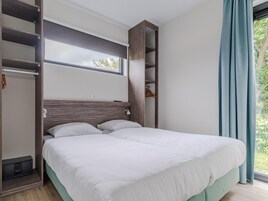 Quarto com cama, guarda-roupa e janela.