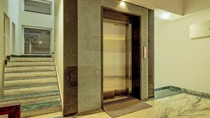 Um elevador com piso de mármore e painel de controle fixado na parede.