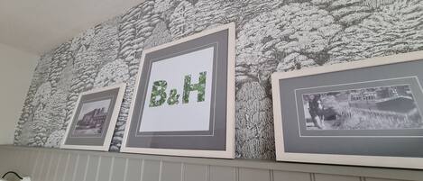 Pareda com três fotografias emolduradas e as letras "B&H" ao centro.