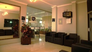 Um hall de hotel com balcão de recepção, área de estar e um espelho grande.