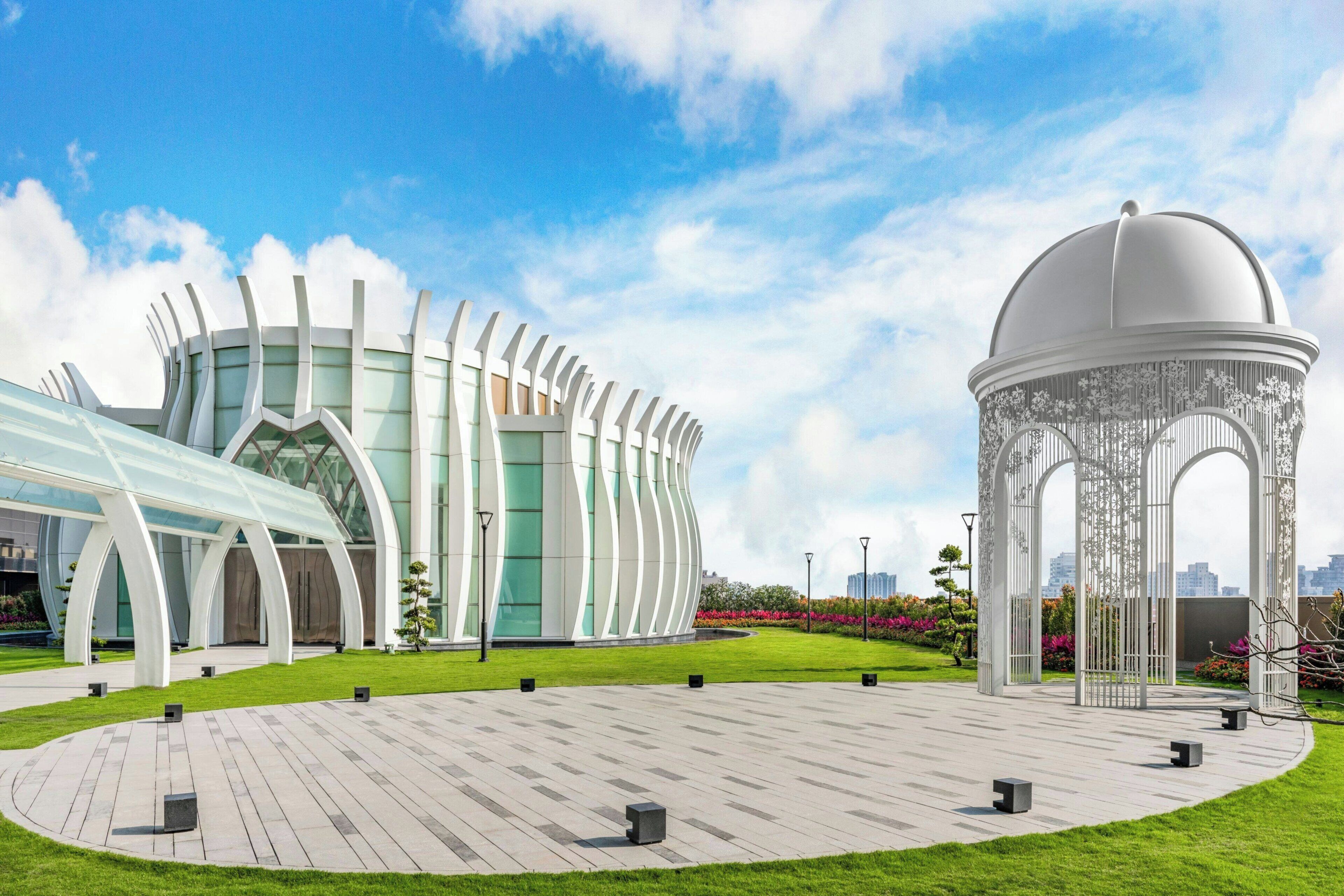 Um edifício moderno com fachada curva singular, estrutura central de vidro e pavilhão em formato de cúpula.