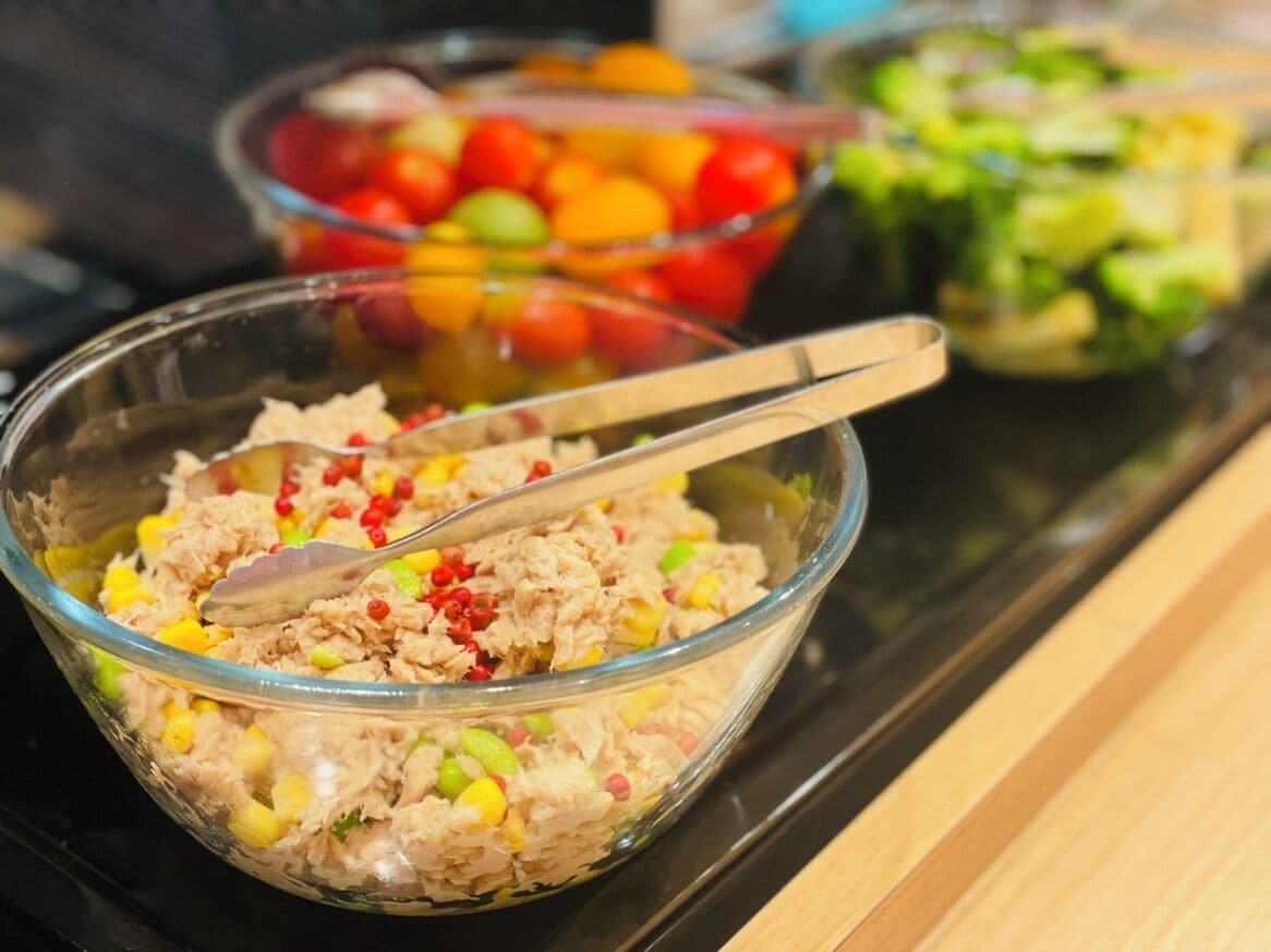Uma salada de atum com legumes sobre uma bancada de cozinha.