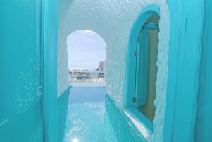 Uma piscina infinita turquesa com vista para o mar e um edifício ao fundo.