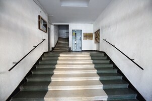 Escada com corrimão em ambos os lados, que dá acesso a um elevador.