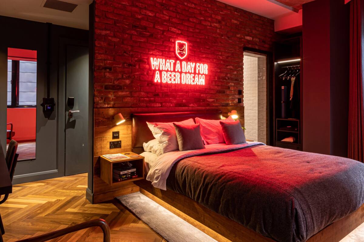 Quarto de hotel moderno com parede de tijolos, um letreiro de neon que diz 