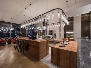Uma área de bar moderna com balcão curvo, diversas opções de assento e luminárias pendentes.